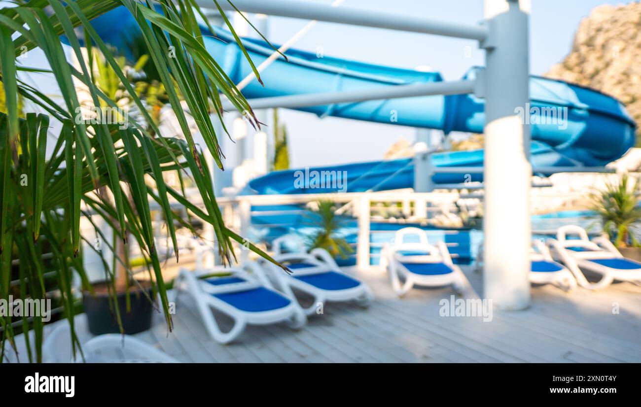 Water Slide Pool Loungers Resort - A blue water slide sits over a pool ...
