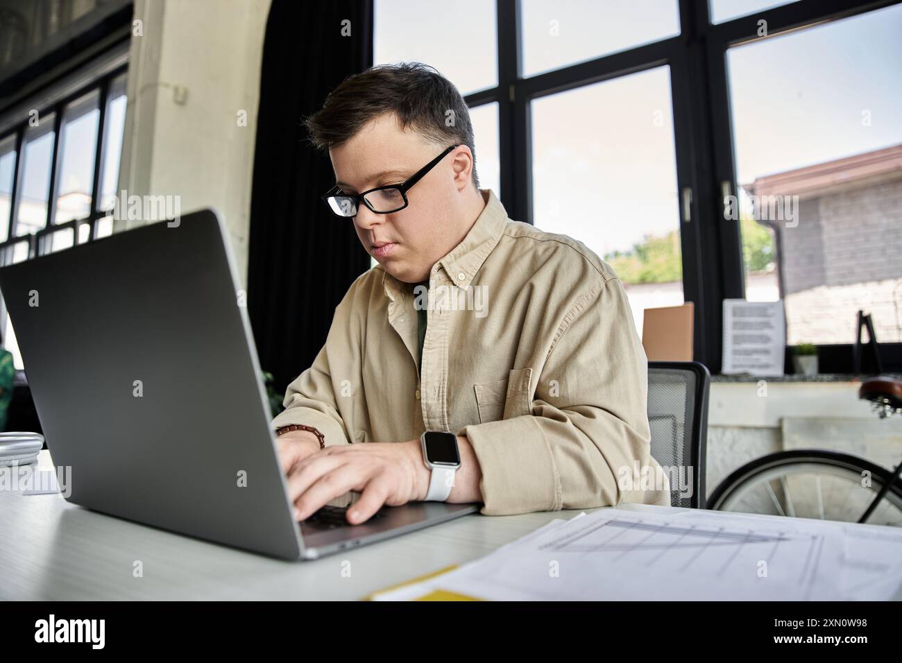 A young man with Down syndrome focuses intently on his work while ...