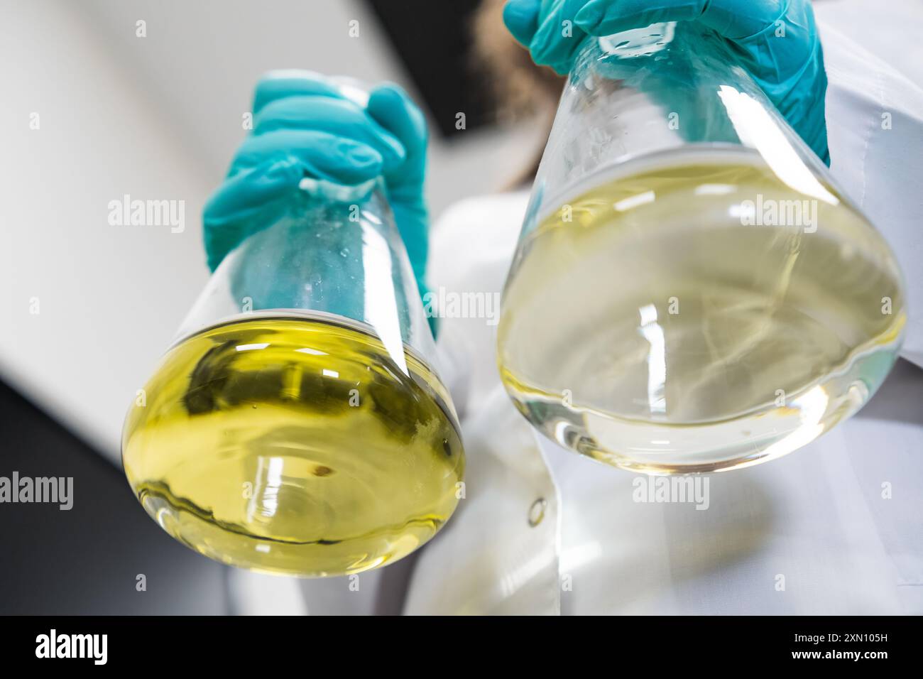 Chemist in lab coat and rubber gloves vigorously shaking yellow samples ...