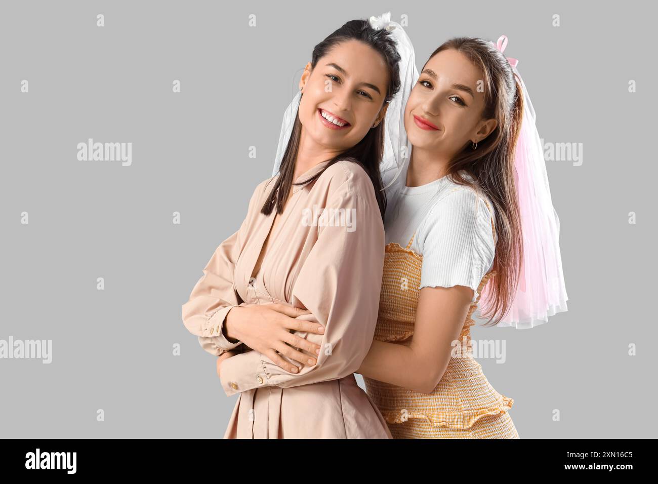 Young woman with her bridesmaid hugging on light background. Hen Party ...