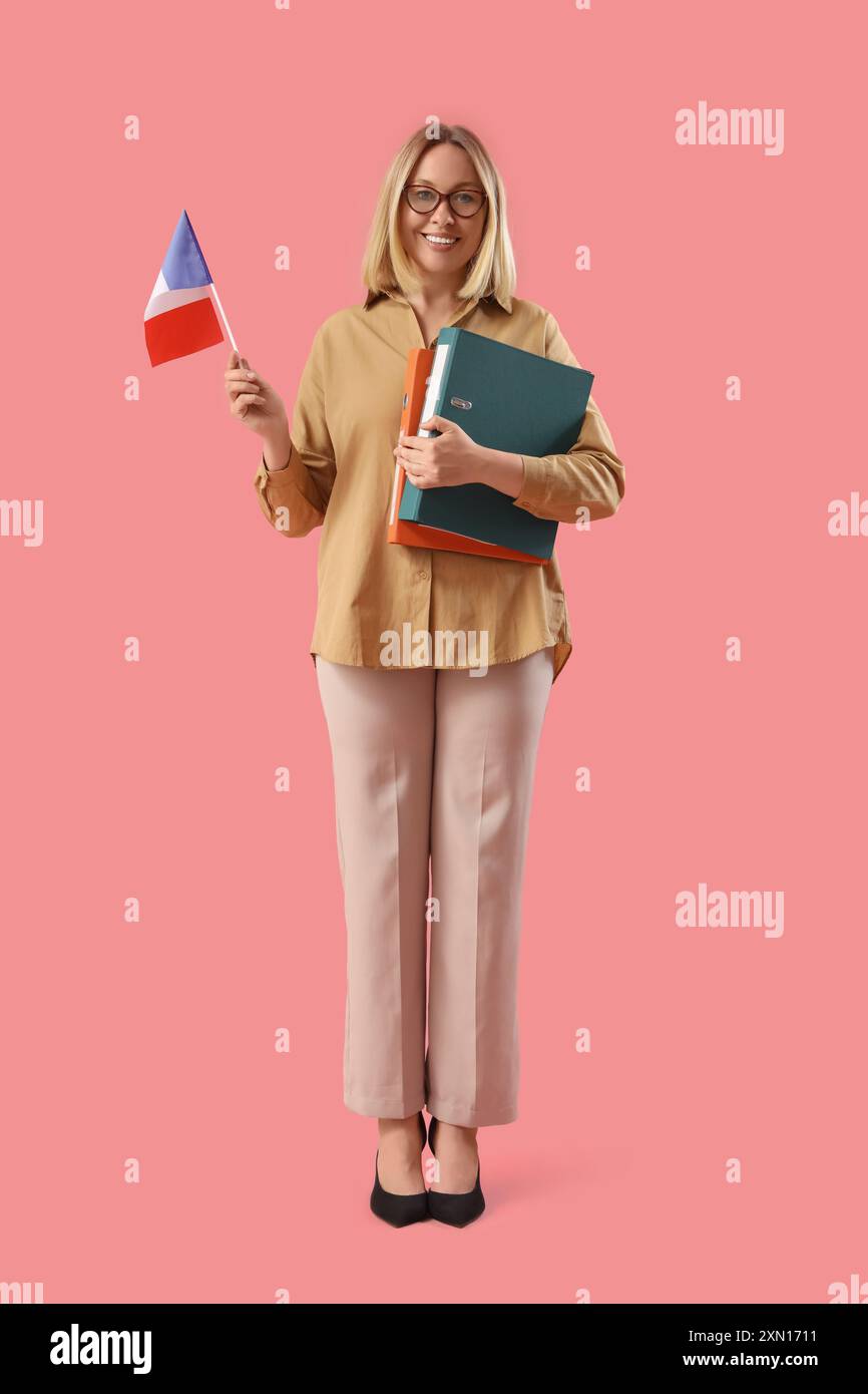 Female French language teacher with flag and folders on pink background ...