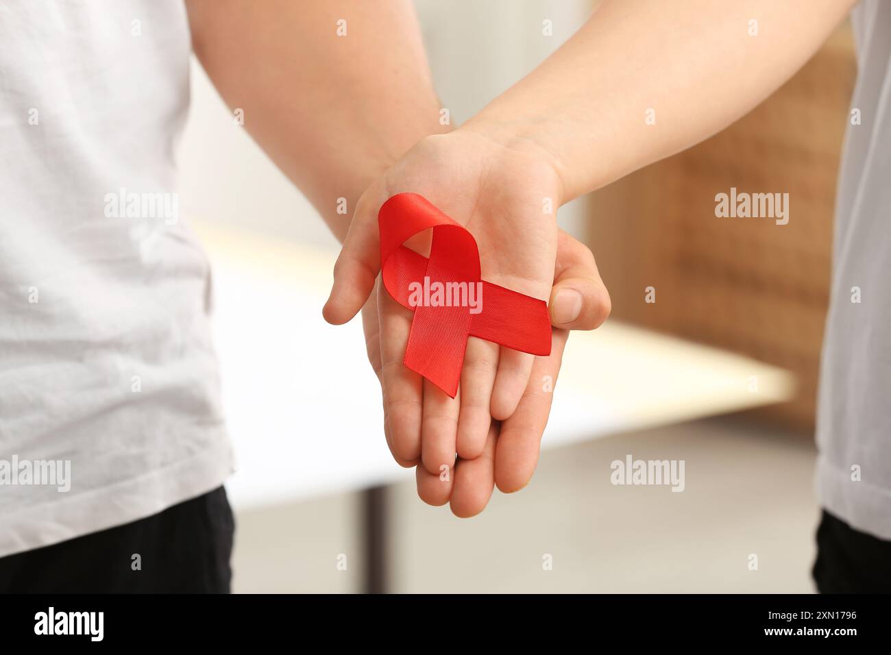 Hands with red ribbon in clinic, closeup. Blood Cancer Awareness Month ...