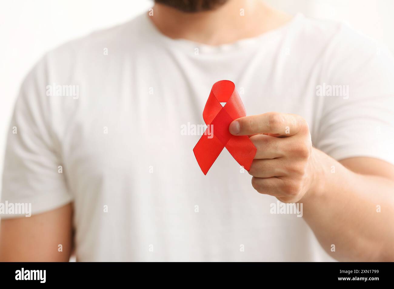 Young man with red ribbon on white background, closeup. Blood Cancer ...