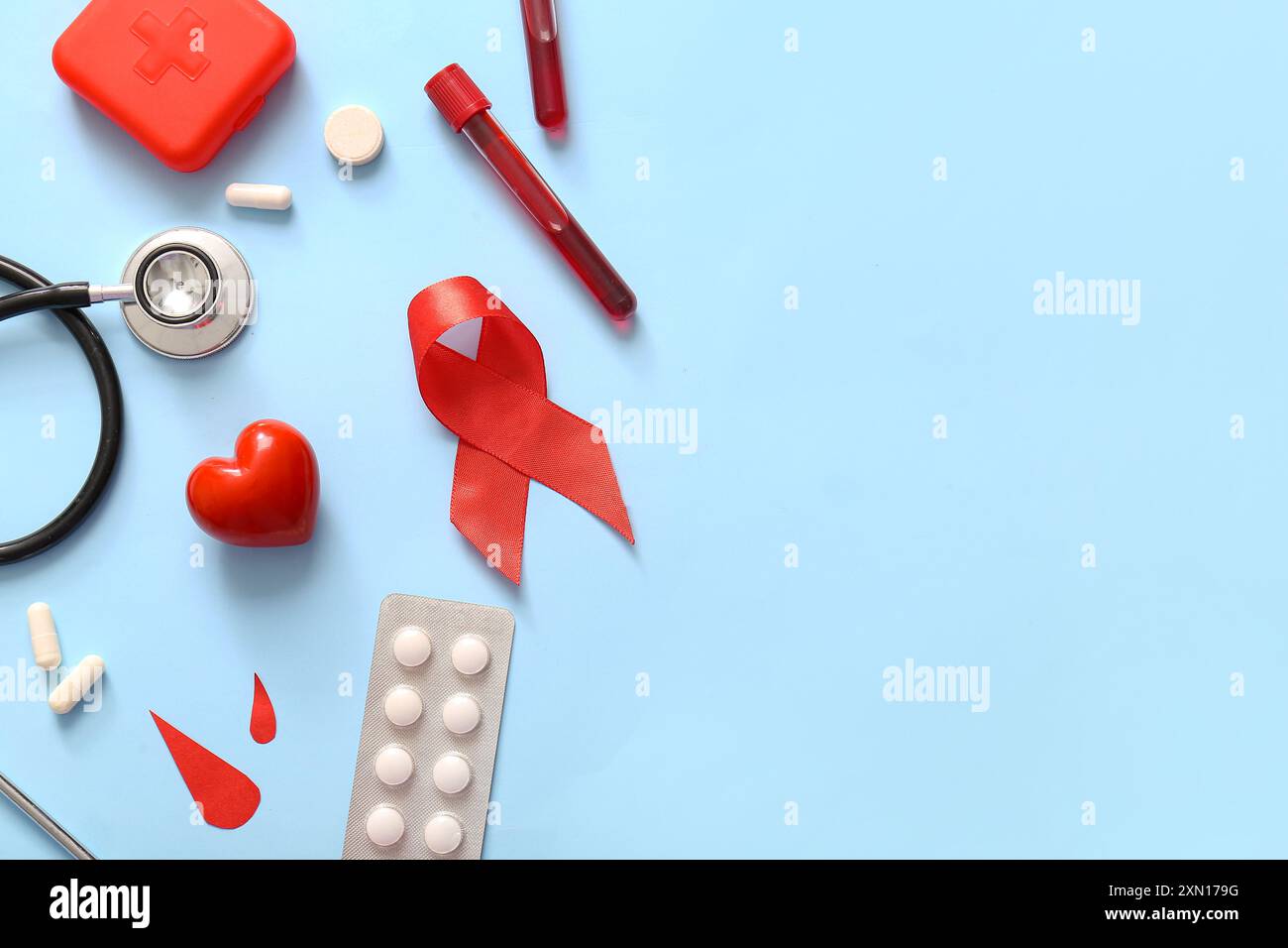 Red ribbon with stethoscope, pills, blood samples and paper drops on ...