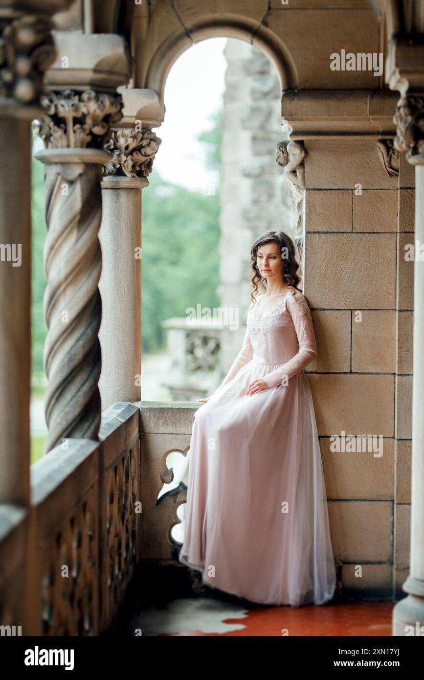 A girl in a light pink dress against the background of a medieval ...