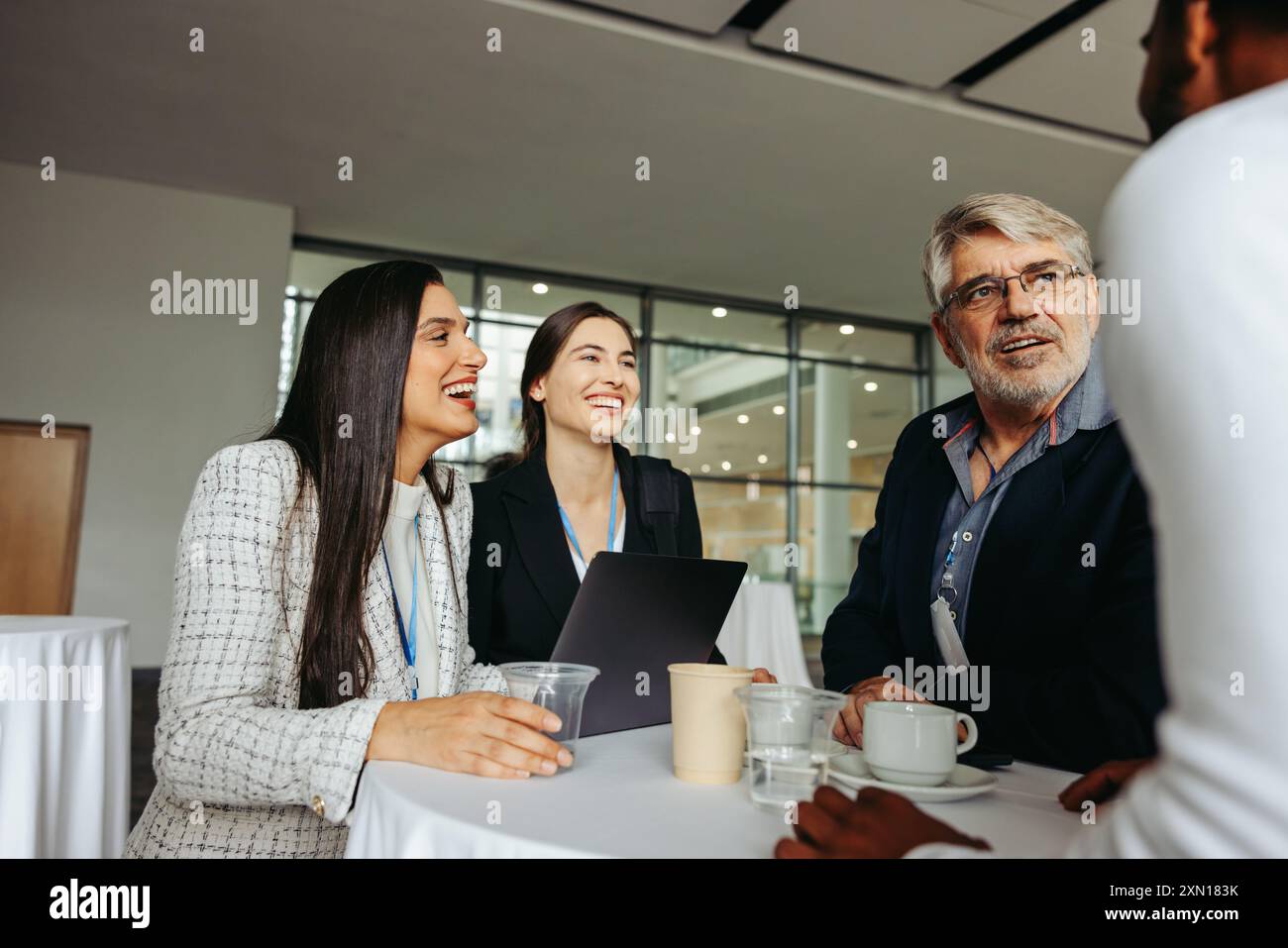 Group of coworkers chatting and networking at a conference table ...