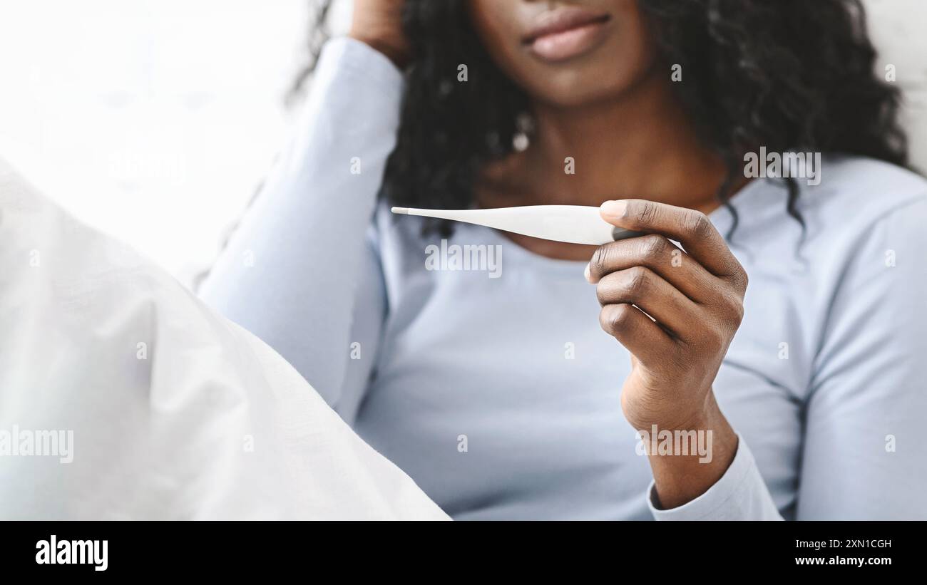 Sick woman with fever checking her temperature in bed Stock Photo - Alamy