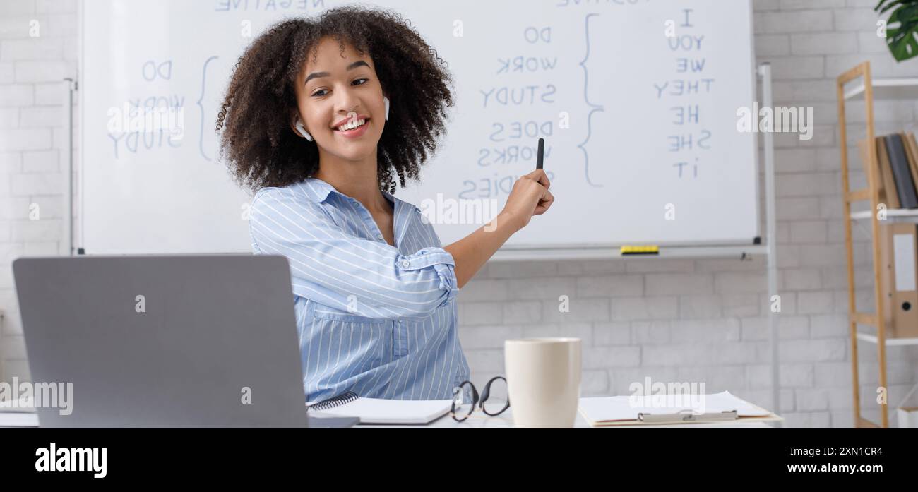 Modern education remotely. Cheerful african american woman points to blackboard and explains ...