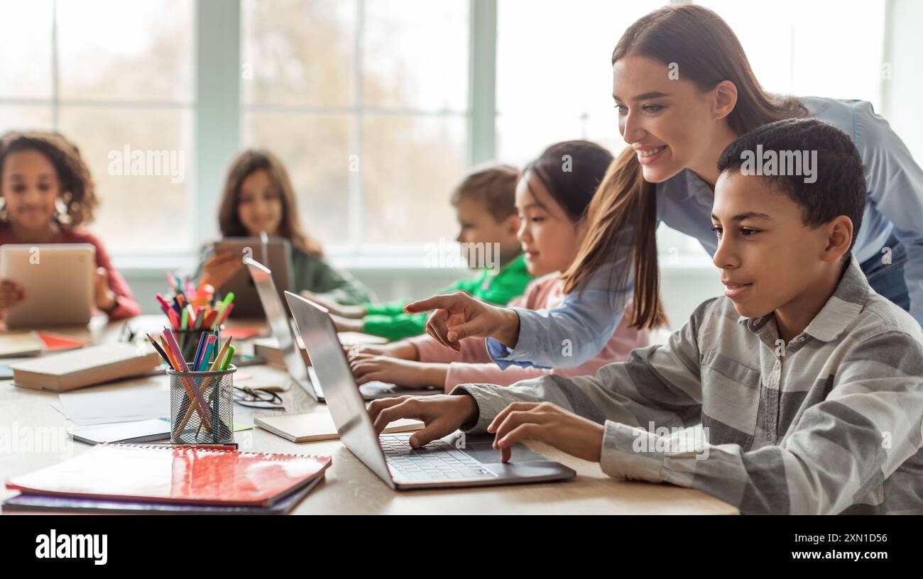 Teacher Teaching Diverse School Kids Using Laptop In Classroom Stock ...