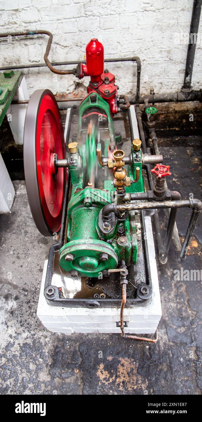 An old industrial machine with a red spinning wheel and various metal ...