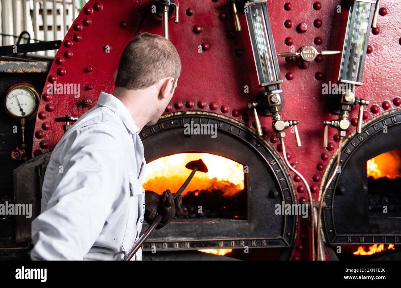 Engineer monitoring and maintaining the boiler system with glowing fire ...