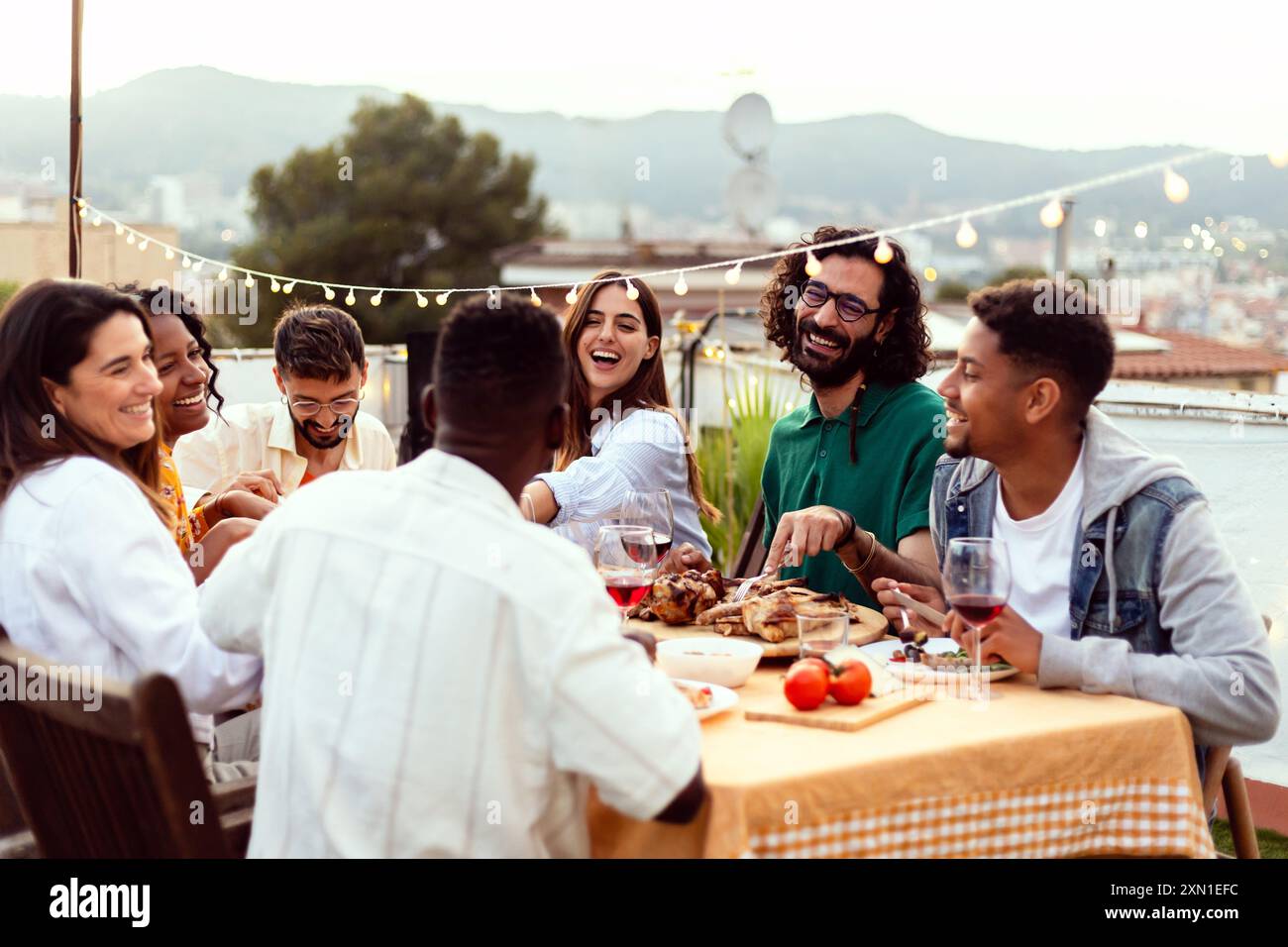 Diverse friends having dinner party outside sitting around table at ...