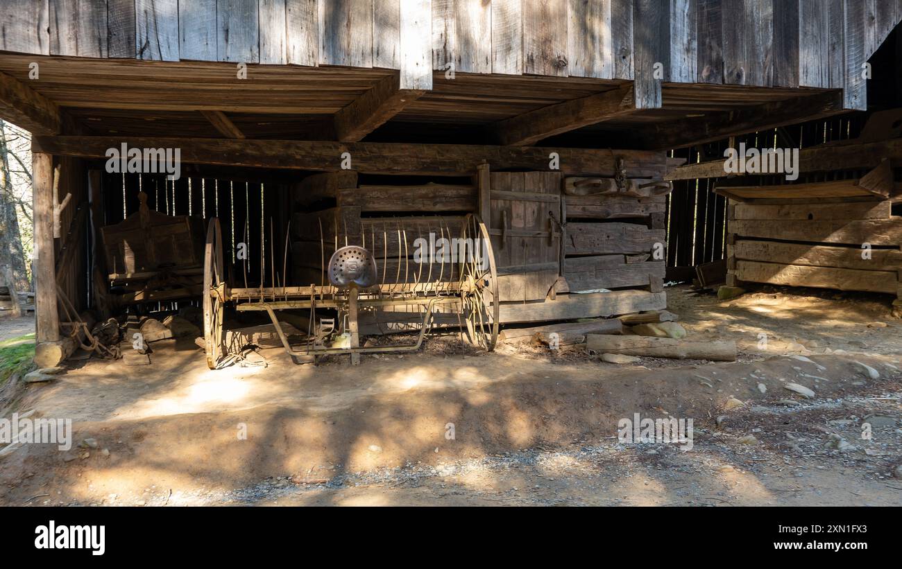 Old metal horse drawn hay rake sits in a historic log shed at Cades ...