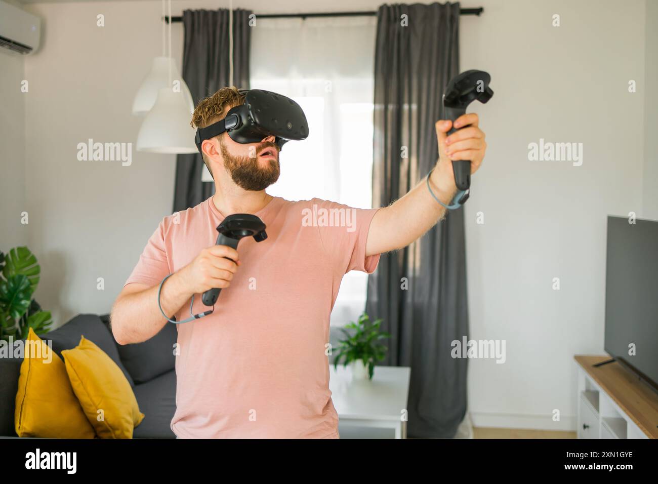 Energetic young man wearing virtual reality headset and holding ...
