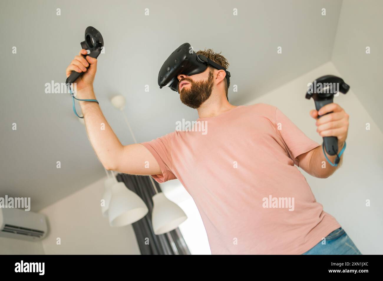 Energetic young man wearing virtual reality headset and holding ...