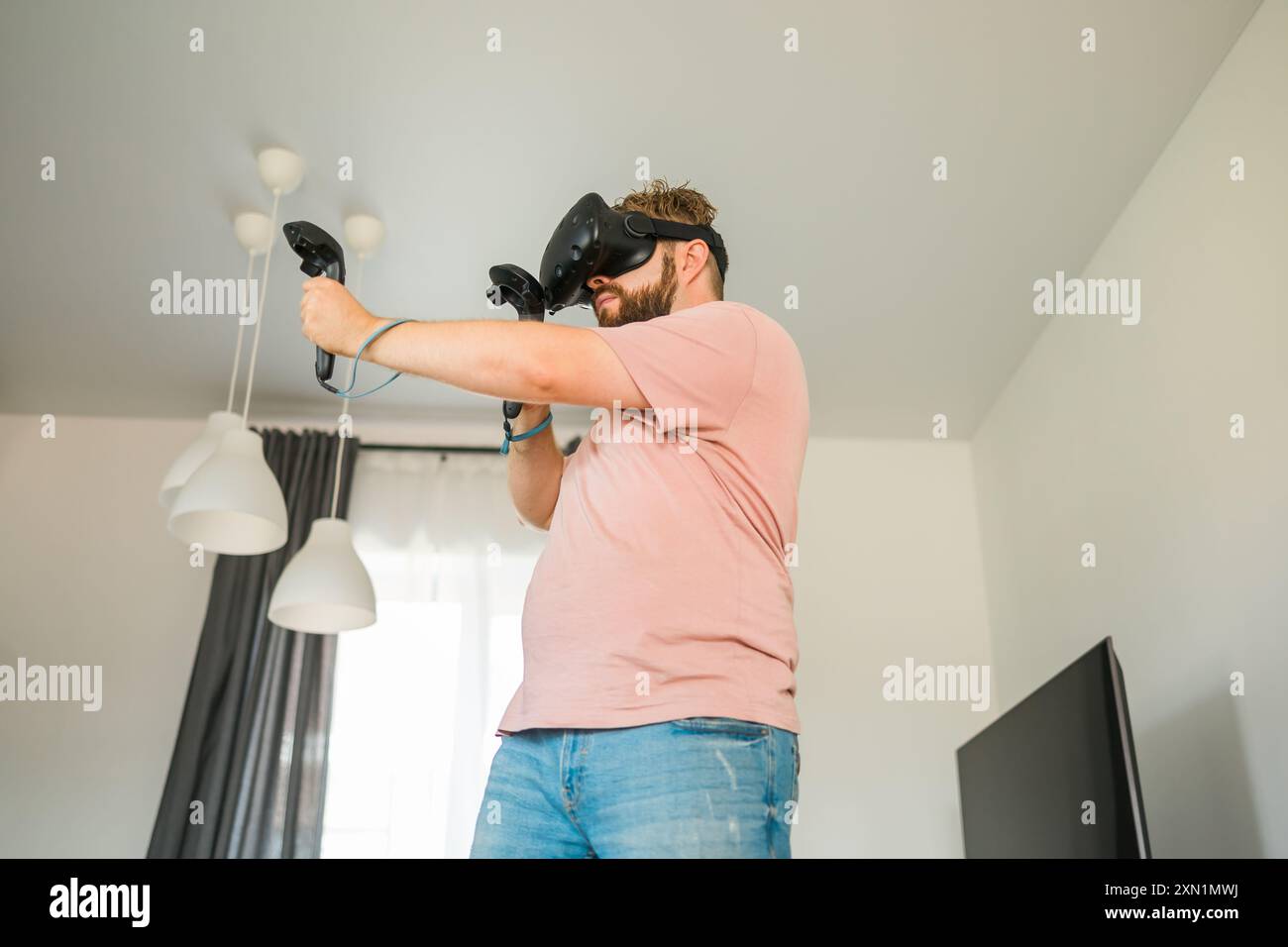 Energetic young man wearing virtual reality headset and holding ...