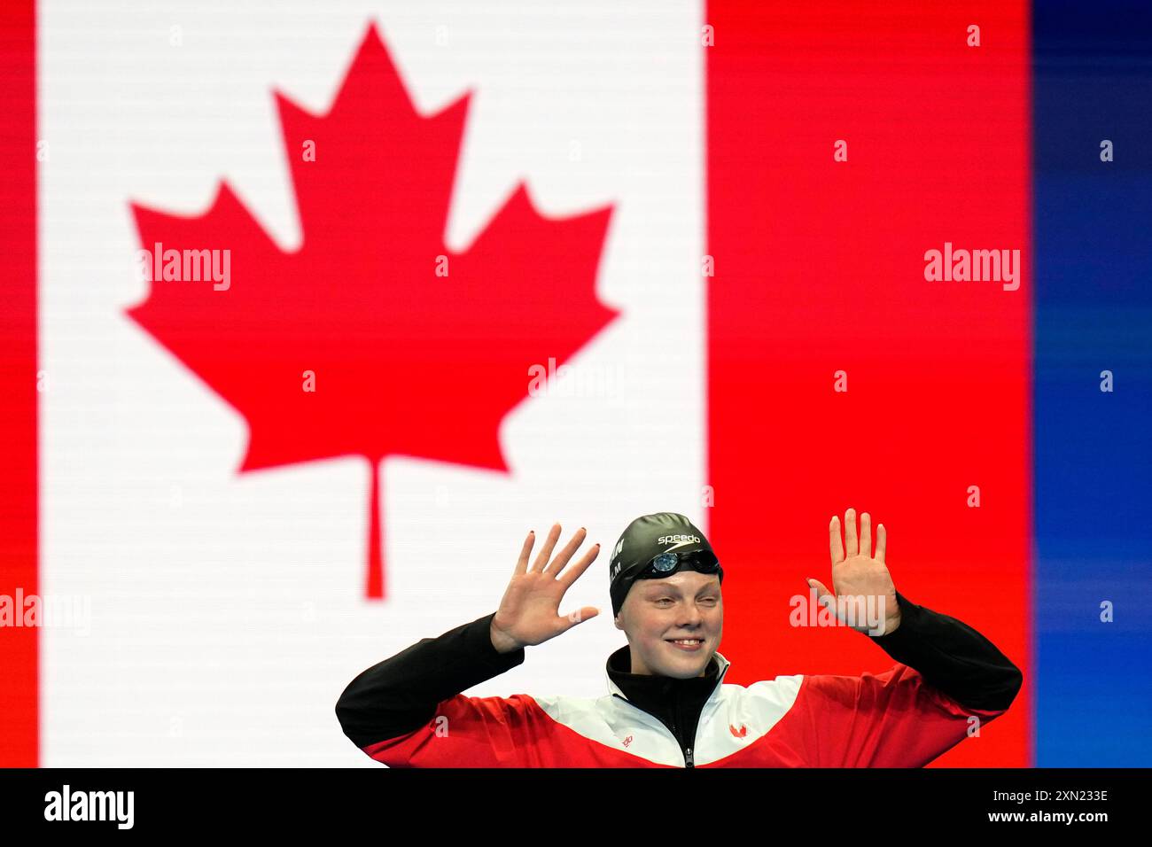 Ingrid Wilm, of Canada, waves as she walks onto the pool deck for the ...
