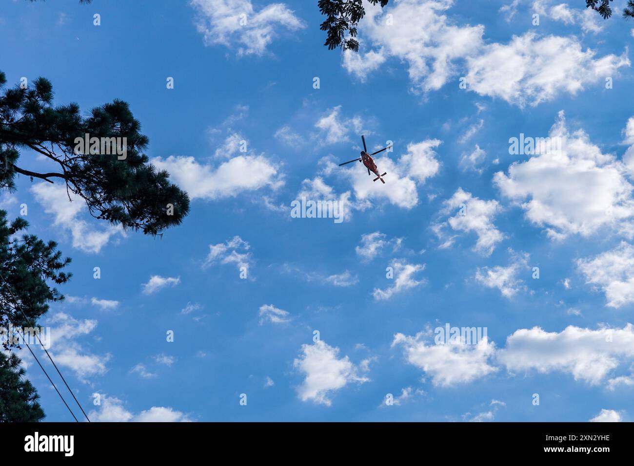 A helicopter flying high in the sky, surrounded by fluffy white clouds ...