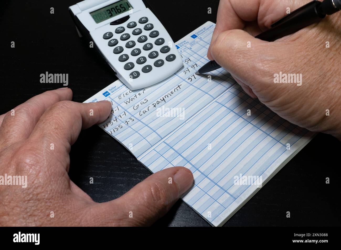 Man making entry in check register with calculator Stock Photo - Alamy