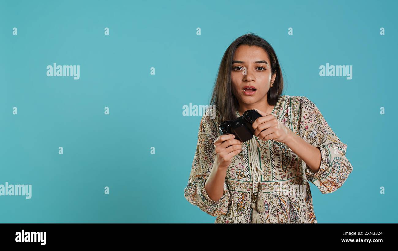 Cheerful woman playing videogames with controller, studio background ...