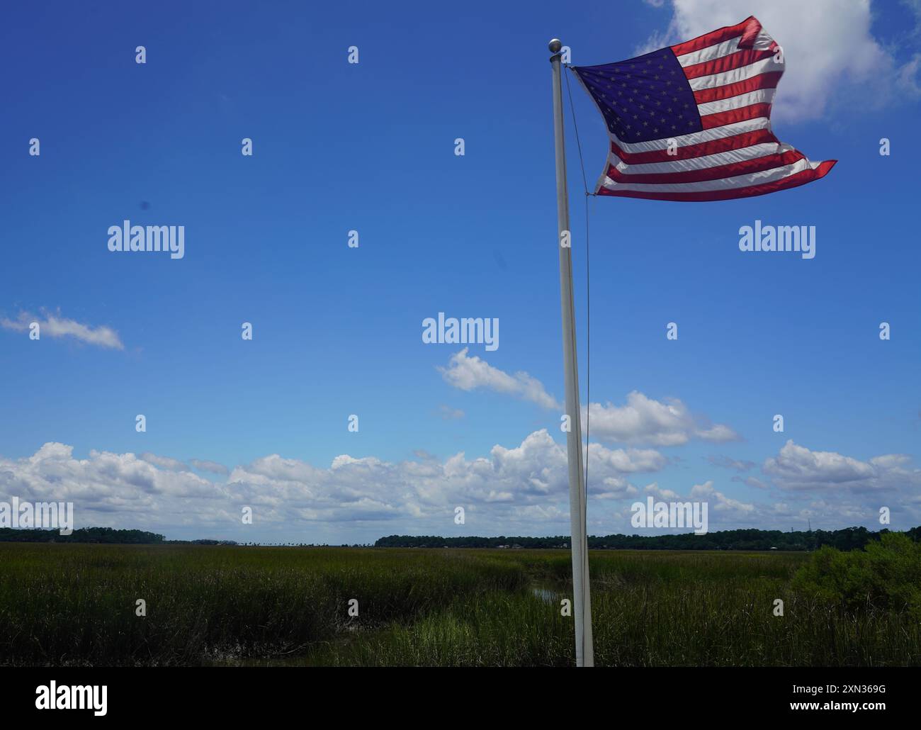 An American flag waving proudly against a clear blue sky, symbolizing ...