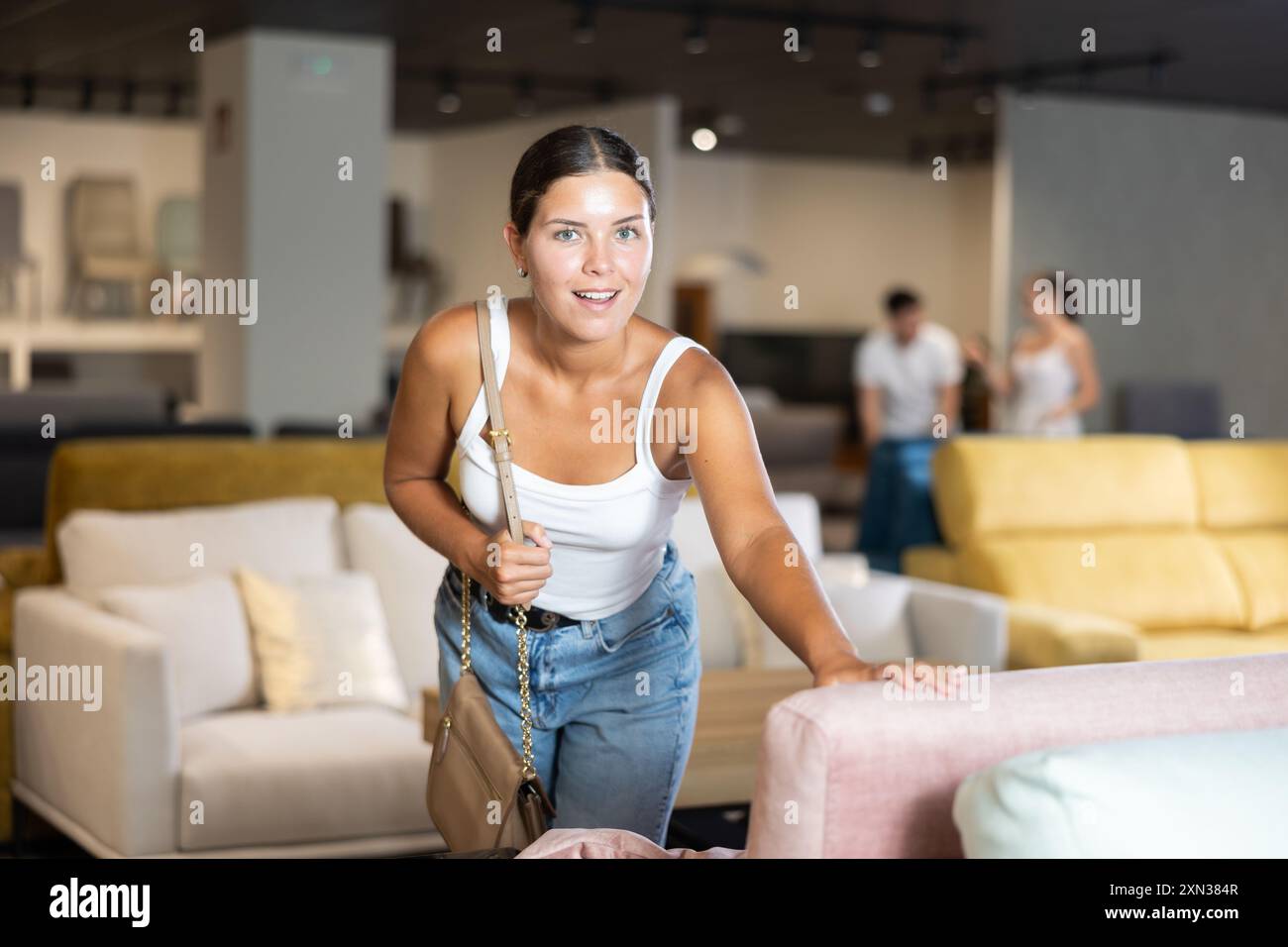 Young woman chooses sofa in store Stock Photo - Alamy