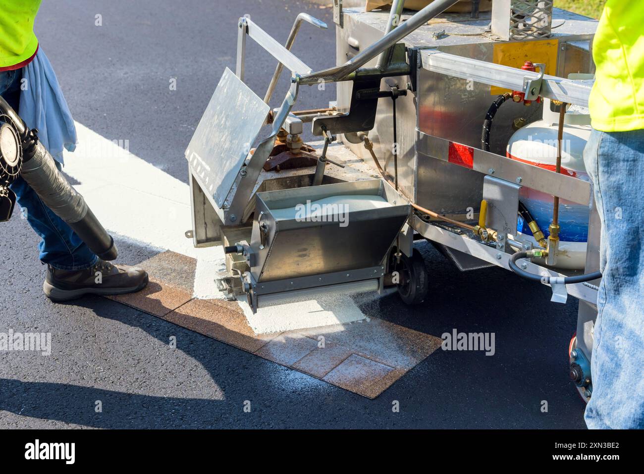 After asphalt is laid on road, workers apply markings signs Stock Photo ...
