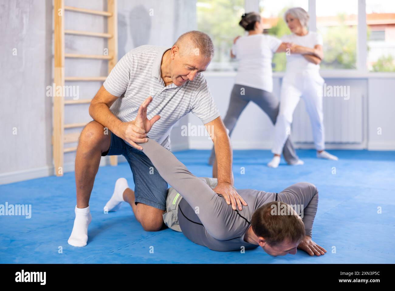 Old man twisting her opponent's arm during self-defense classes Stock ...