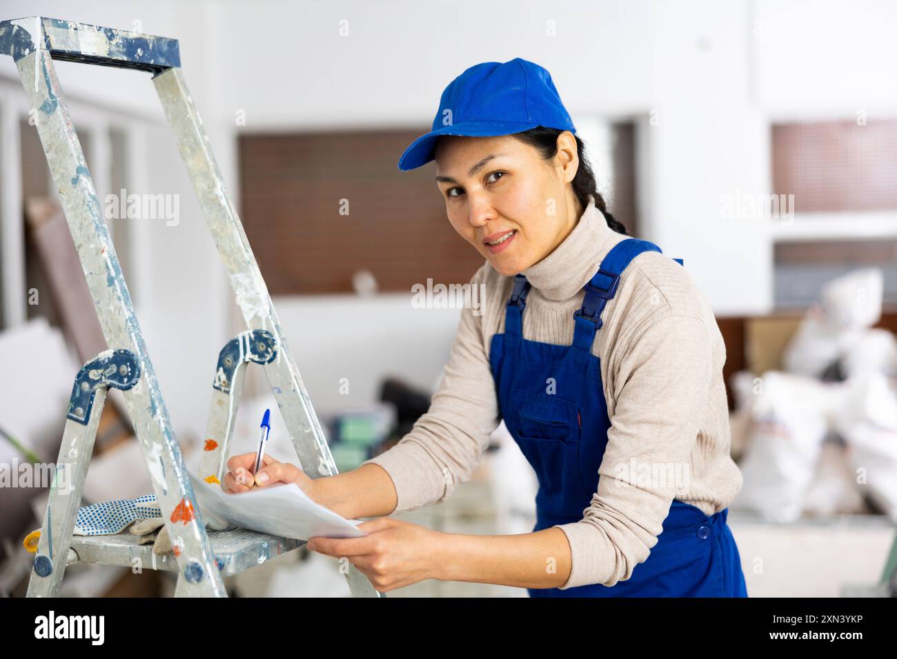 Positive woman builder filling project documentation Stock Photo - Alamy