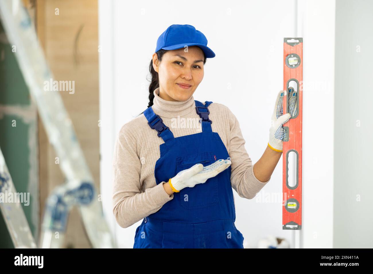 Woman builder using building level measures the vertical of wall Stock ...