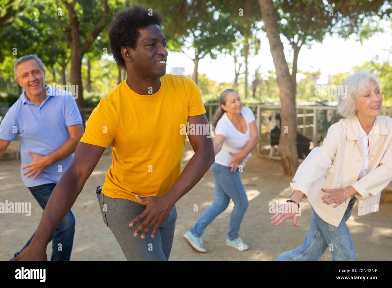 Positive mature women and men practicing vigorous dance movements in ...