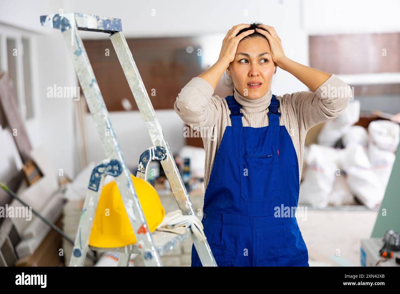 Frustrated woman builder holding head while standing in construction ...
