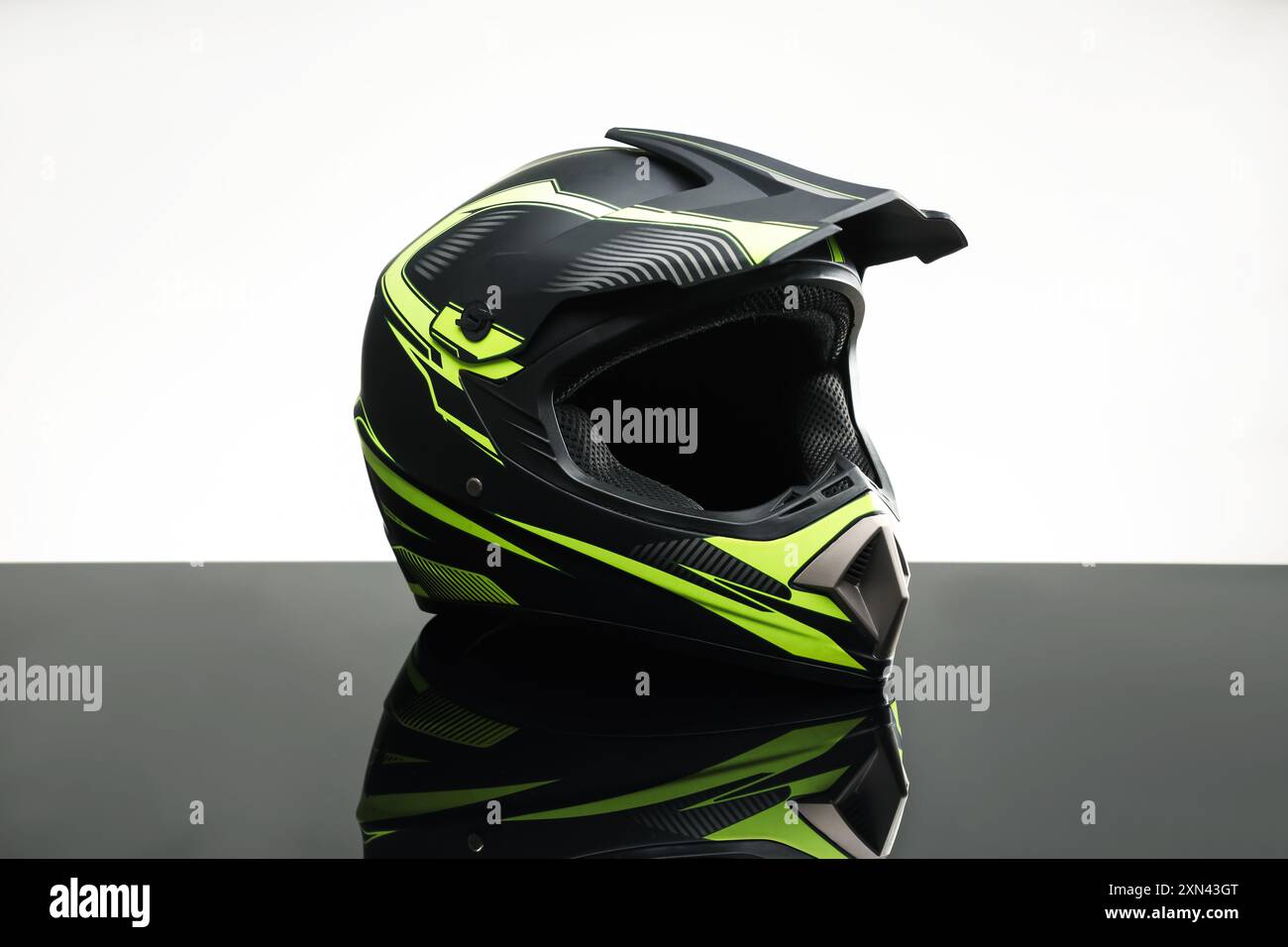 Modern motorcycle helmet with visor on mirror surface against light ...