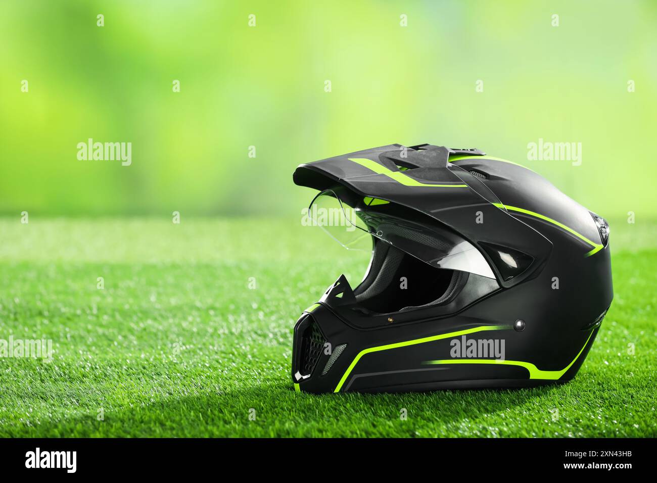 Modern motorcycle helmet with visor on green grass, space for text ...