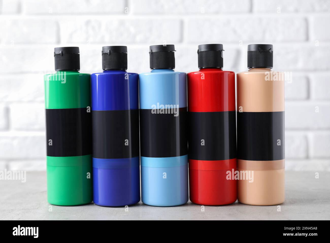 Acrylic paints of different colors in bottles on light table Stock ...