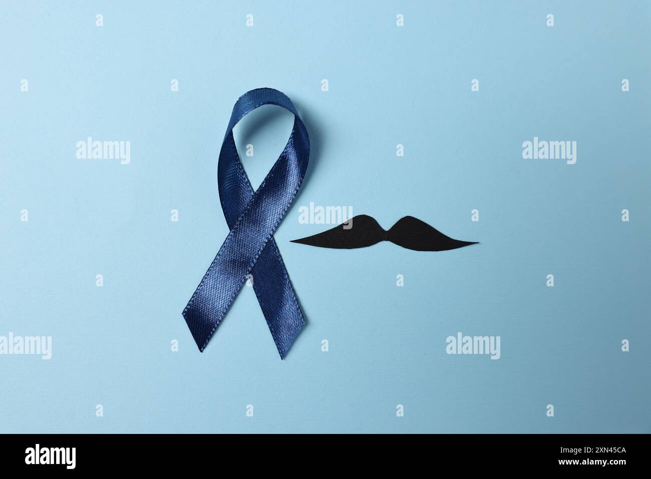 Dark blue ribbon and fake mustache on color background, top view ...