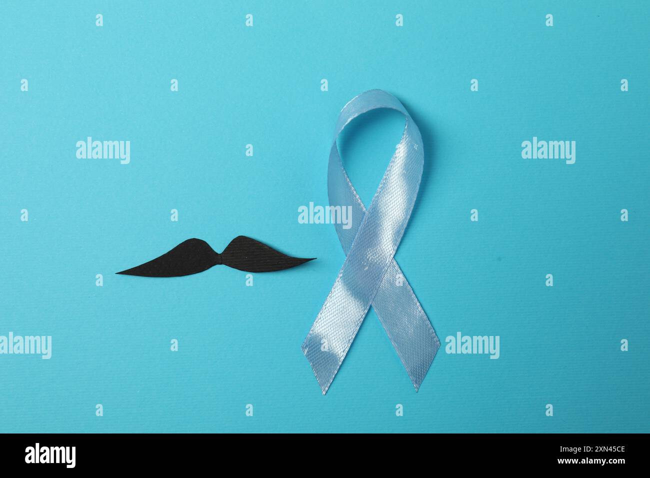 Light blue ribbon and fake mustache on color background, top view ...