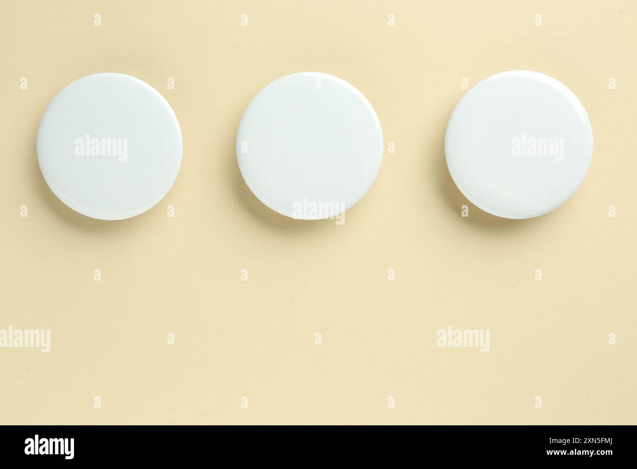 White button badges on beige background, flat lay. Mockup for design ...