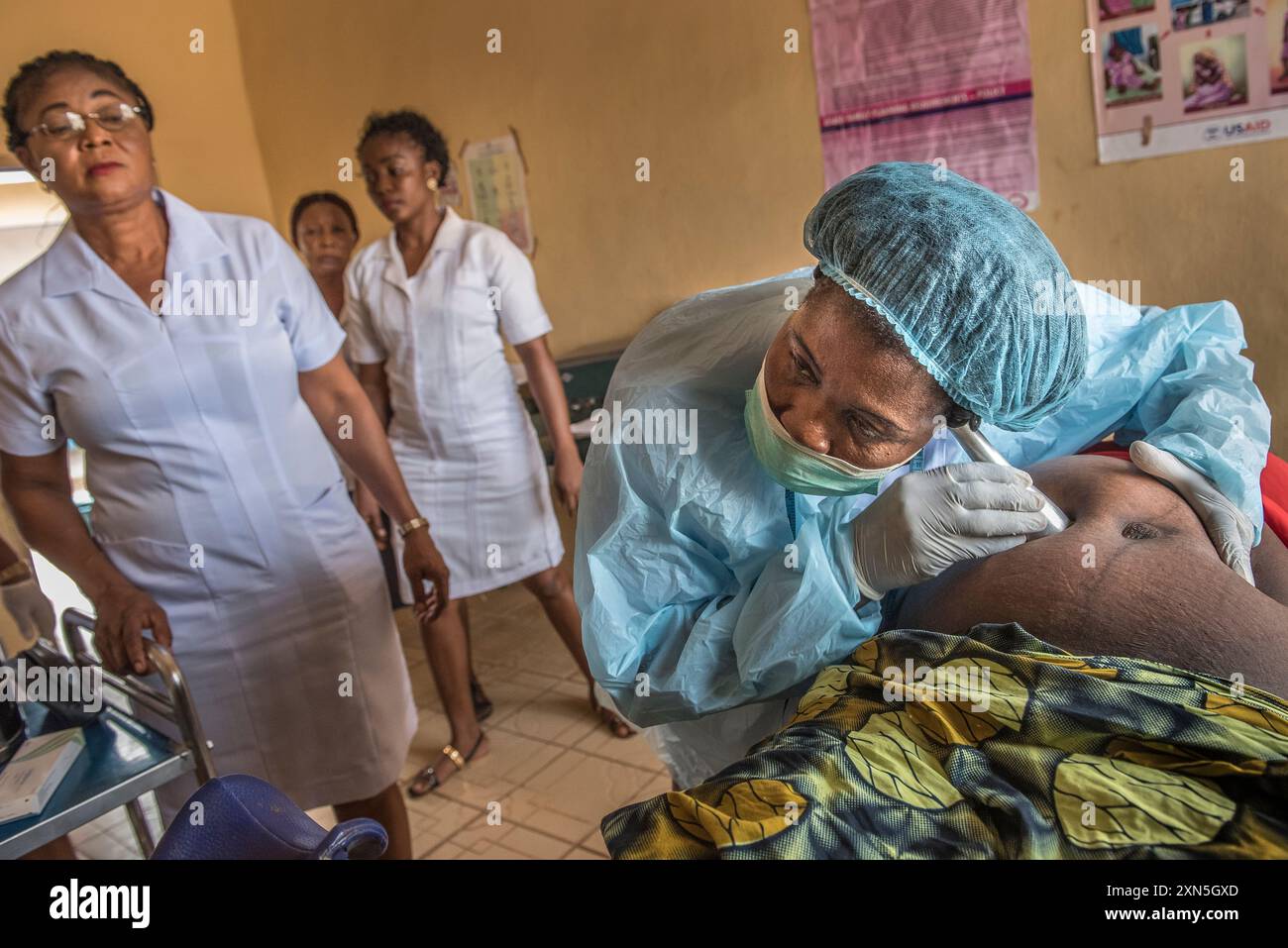 Nurse using a Pinard horn stethoscope to listen to a foetus's heart ...