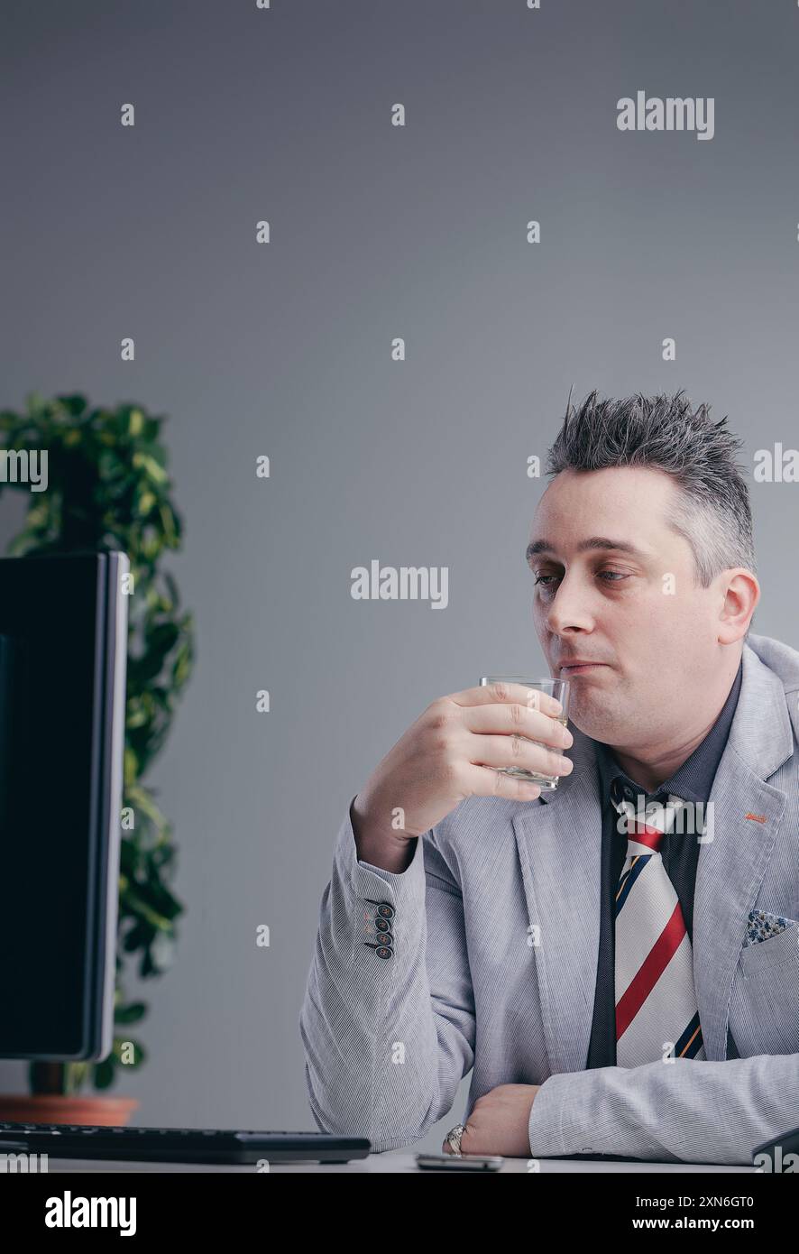 Stressed manager drinks alcohol at office desk, reflecting on job ...