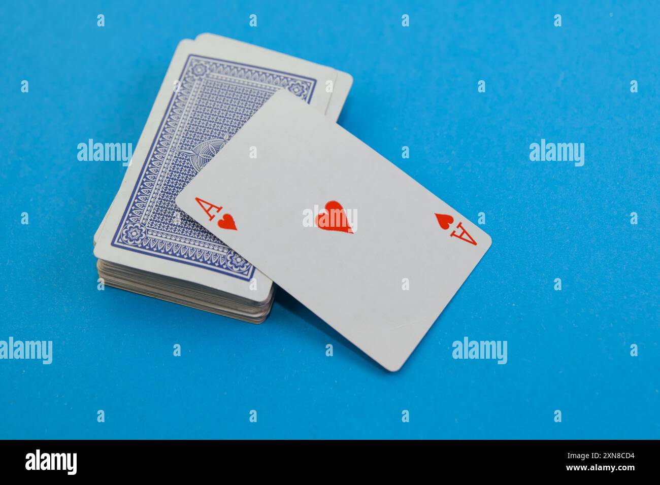 A single Ace of Hearts playing card lies face up against a vibrant blue ...