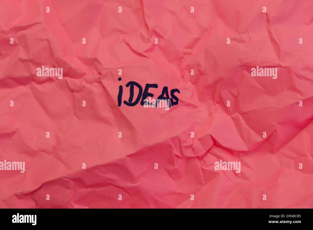 Crumpled pink paper with the word "IDEAS" boldly written. A visual for ...