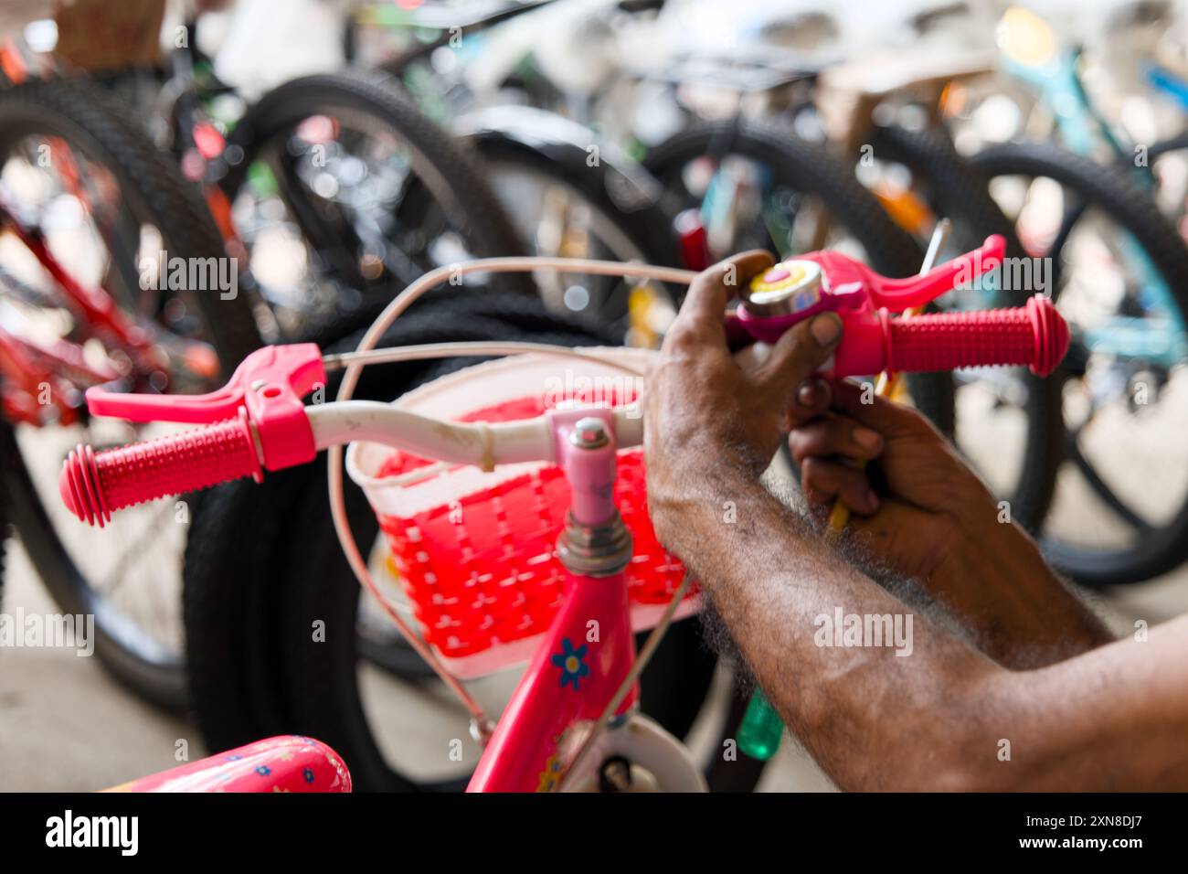 Hands carefully assemble a bright pink children's bike, ready for a ...
