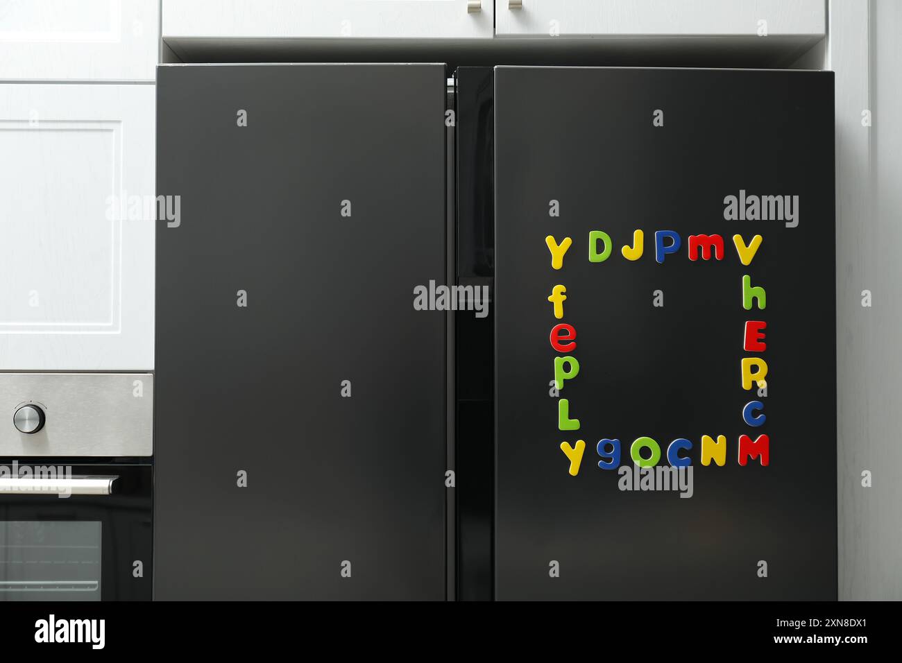 Frame made of many bright magnetic letters on fridge indoors. Learning ...