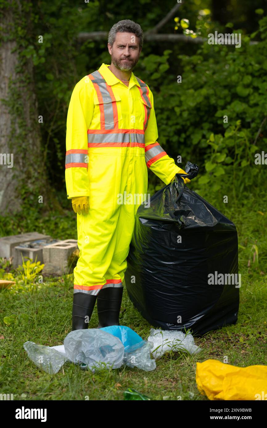 Environment plastic pollution. Volunteer collecting trash in the forest and holding a garbage ...