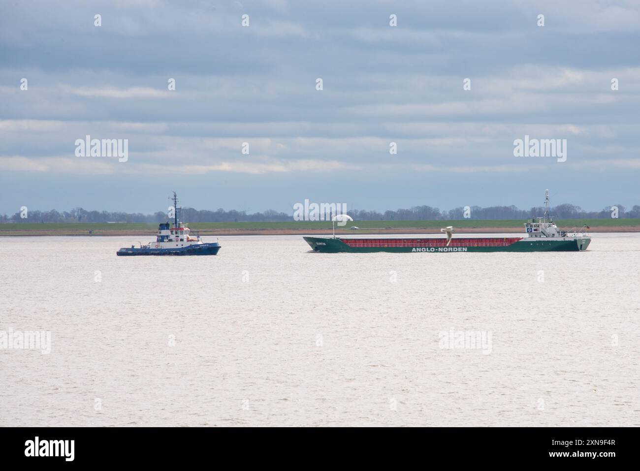 A tug from the pilot service passes a freight ship entering the Elbe ...