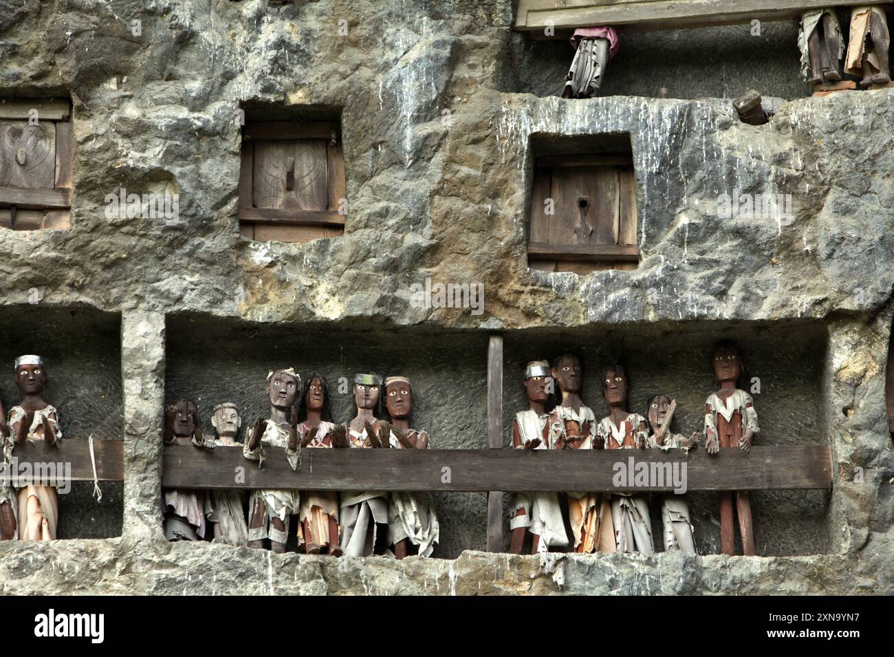 Stone grave openings and wooden effigies on a cliff at a traditional ...
