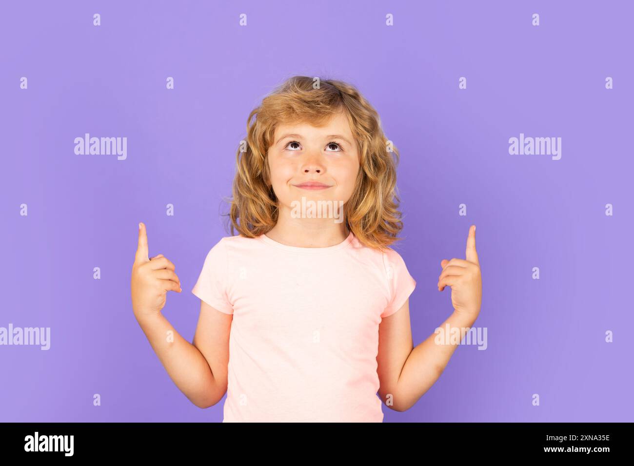 Child pointing up on isolated studio background. Kid with index finger ...