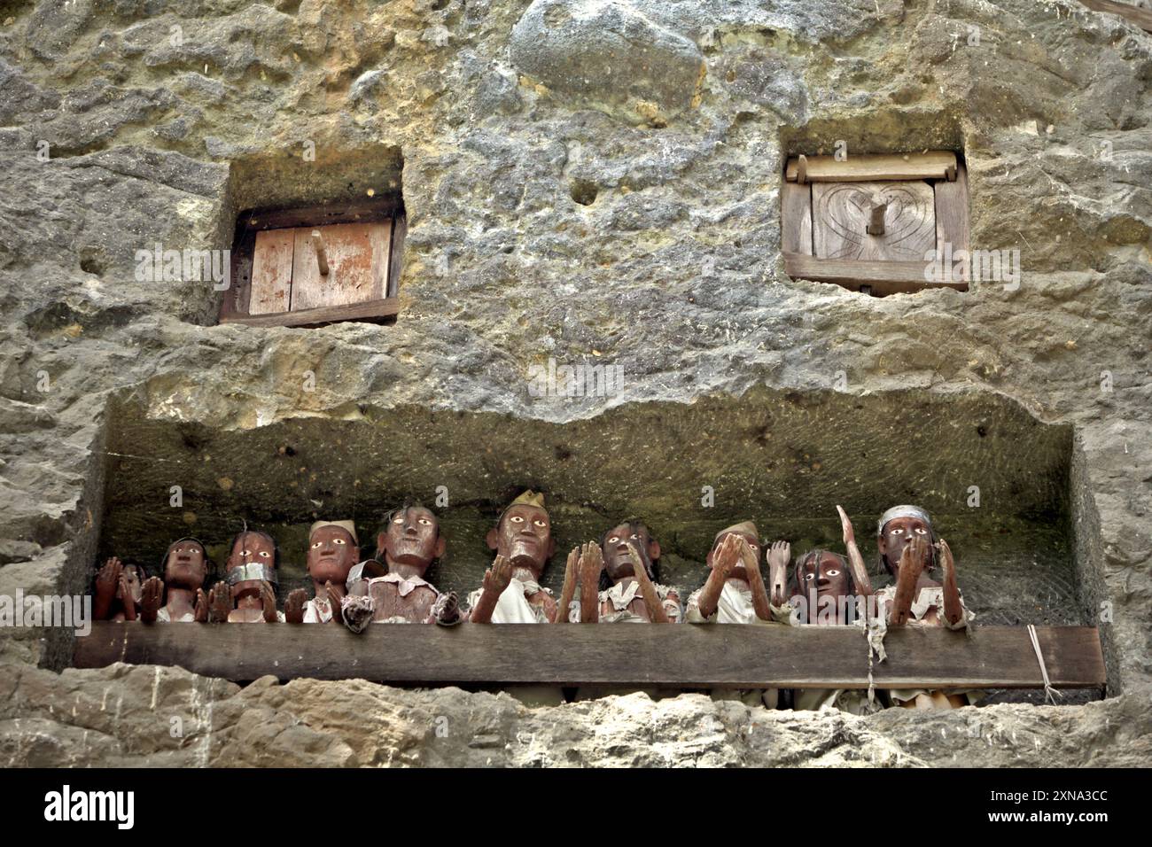Stone grave openings and wooden effigies on a cliff at a traditional ...