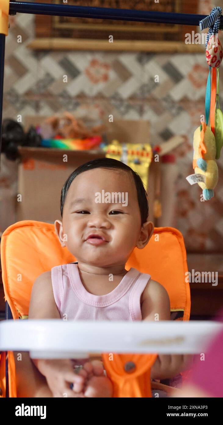 baby boy sitting on a swing chair, cute boy expression pouting mouth ...